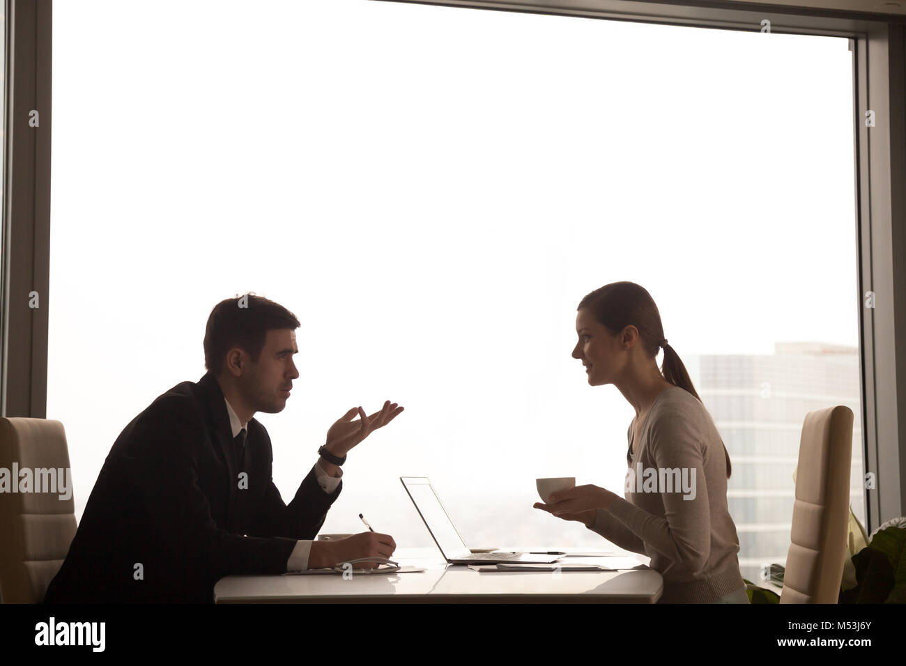 Employees talking about business at desk in office Stock Photo - Alamy