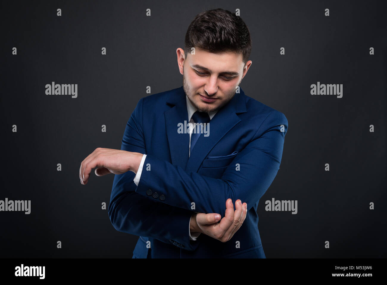 Businessman in modern suit suffers intense elbow pain on dark ...