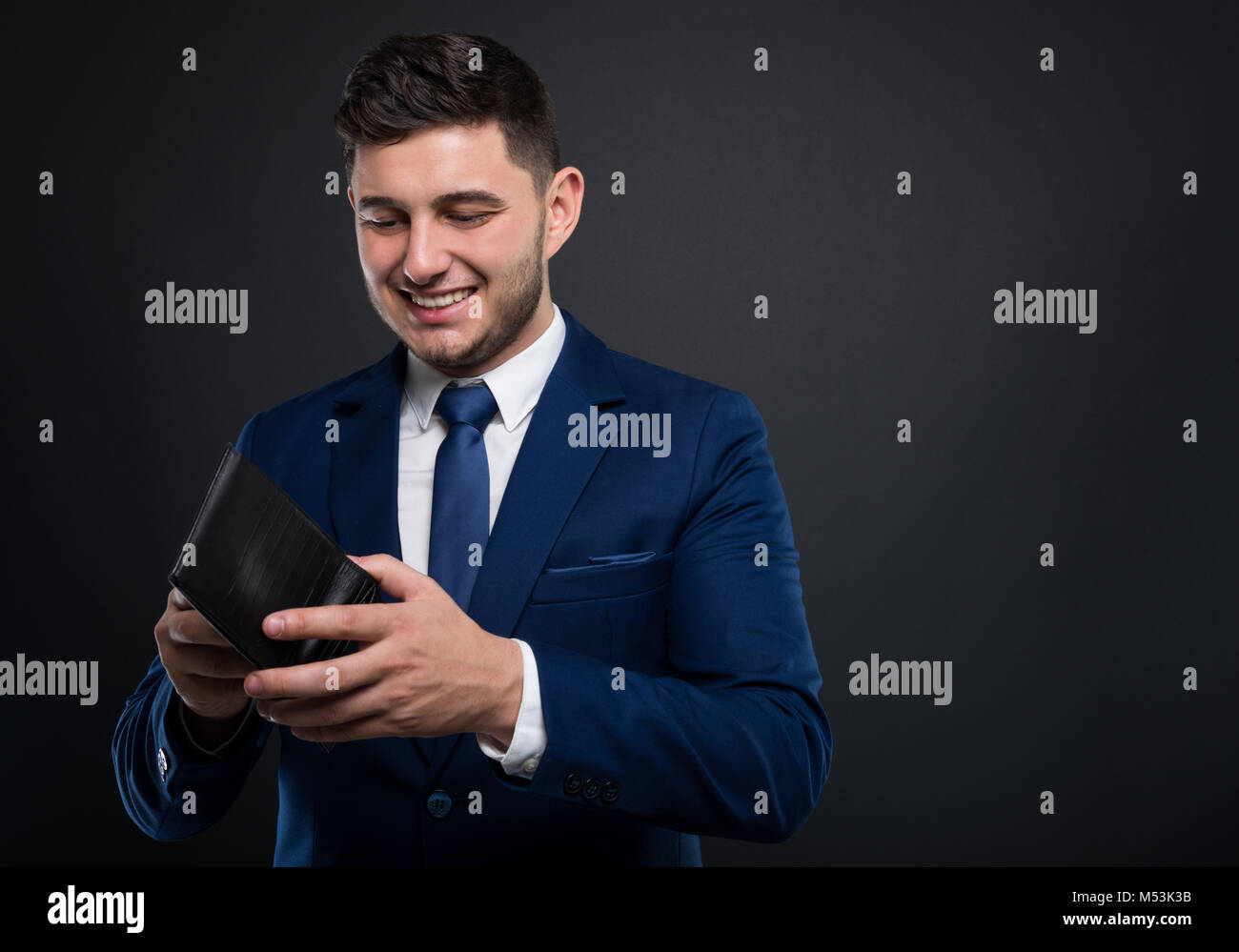 Elegant man in suit standing and checking his wallet while smiling ...