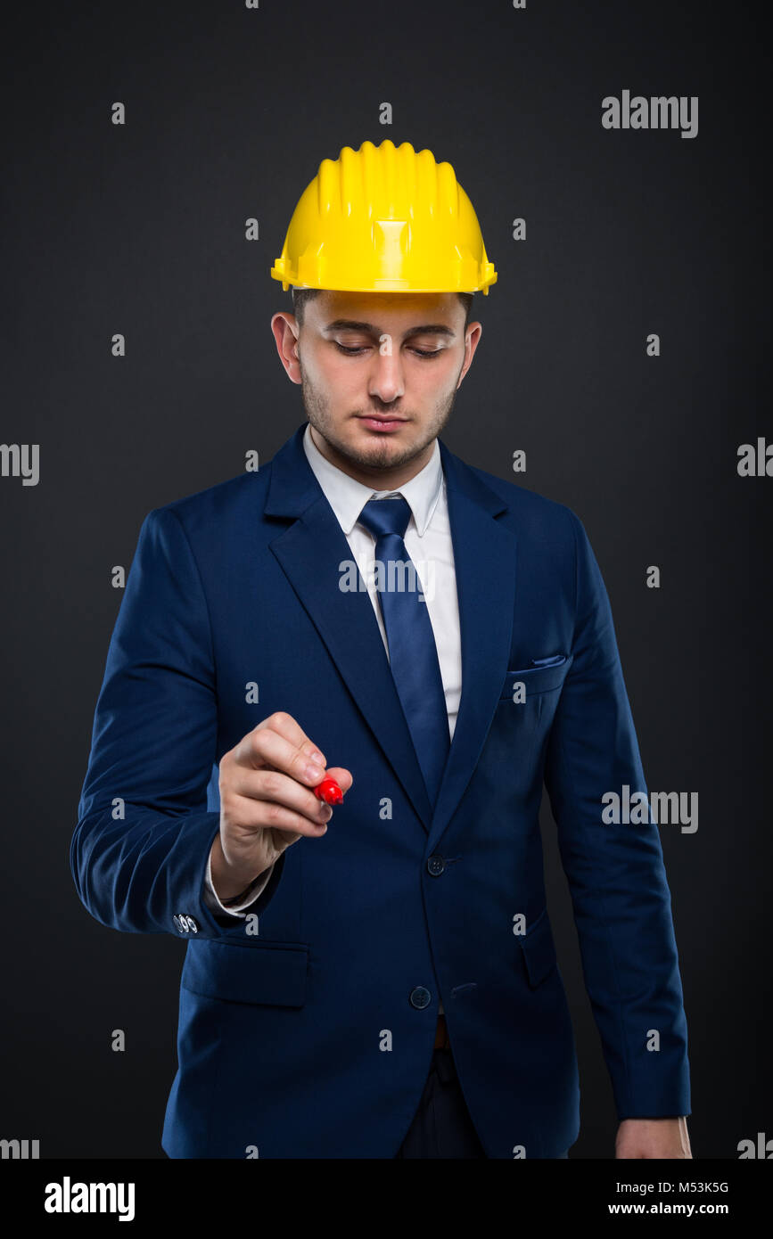 Male engineer with protection helmet writing on screen with marker ...