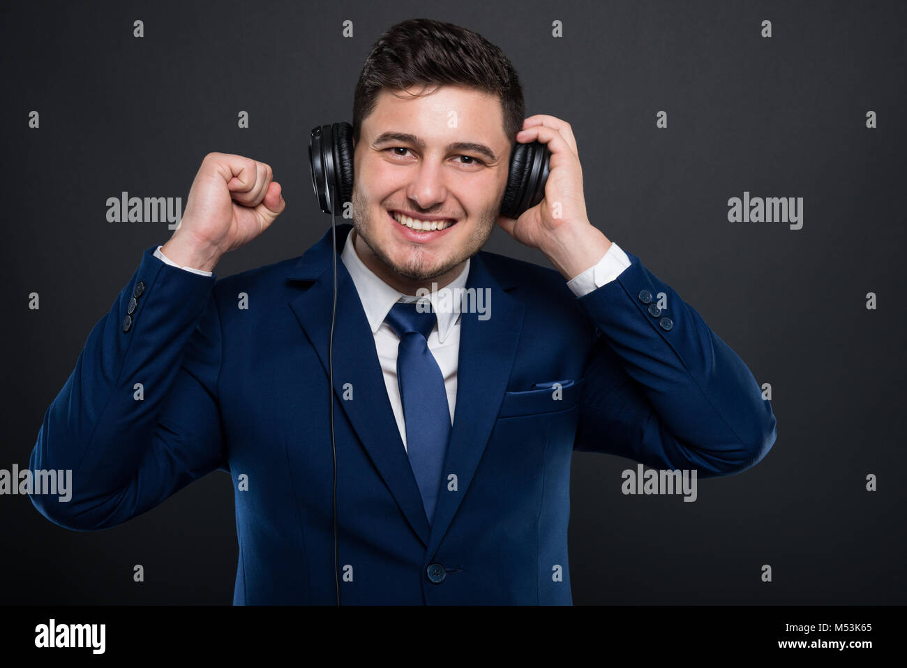 Young director listening music and dancing on dark studio background ...