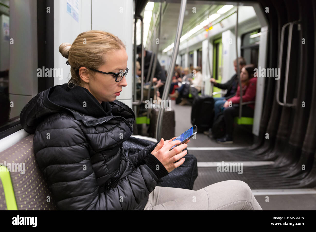 Young girl reading from mobile phone screen in metro Stock Photo - Alamy