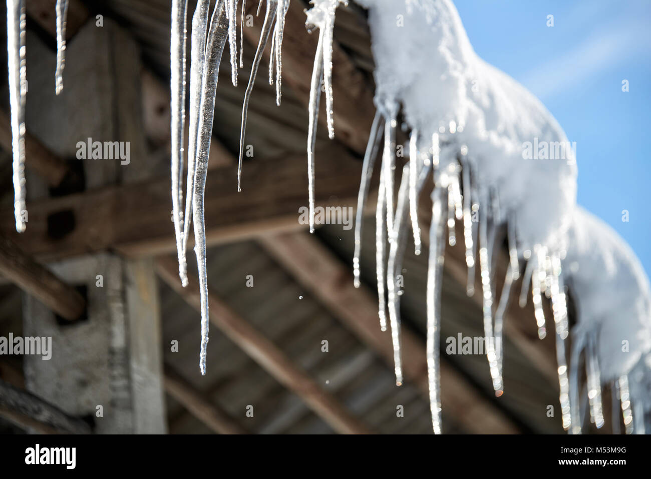 Icicles and Snow Overhanging a Roof. Row of long and big icicles on the ...