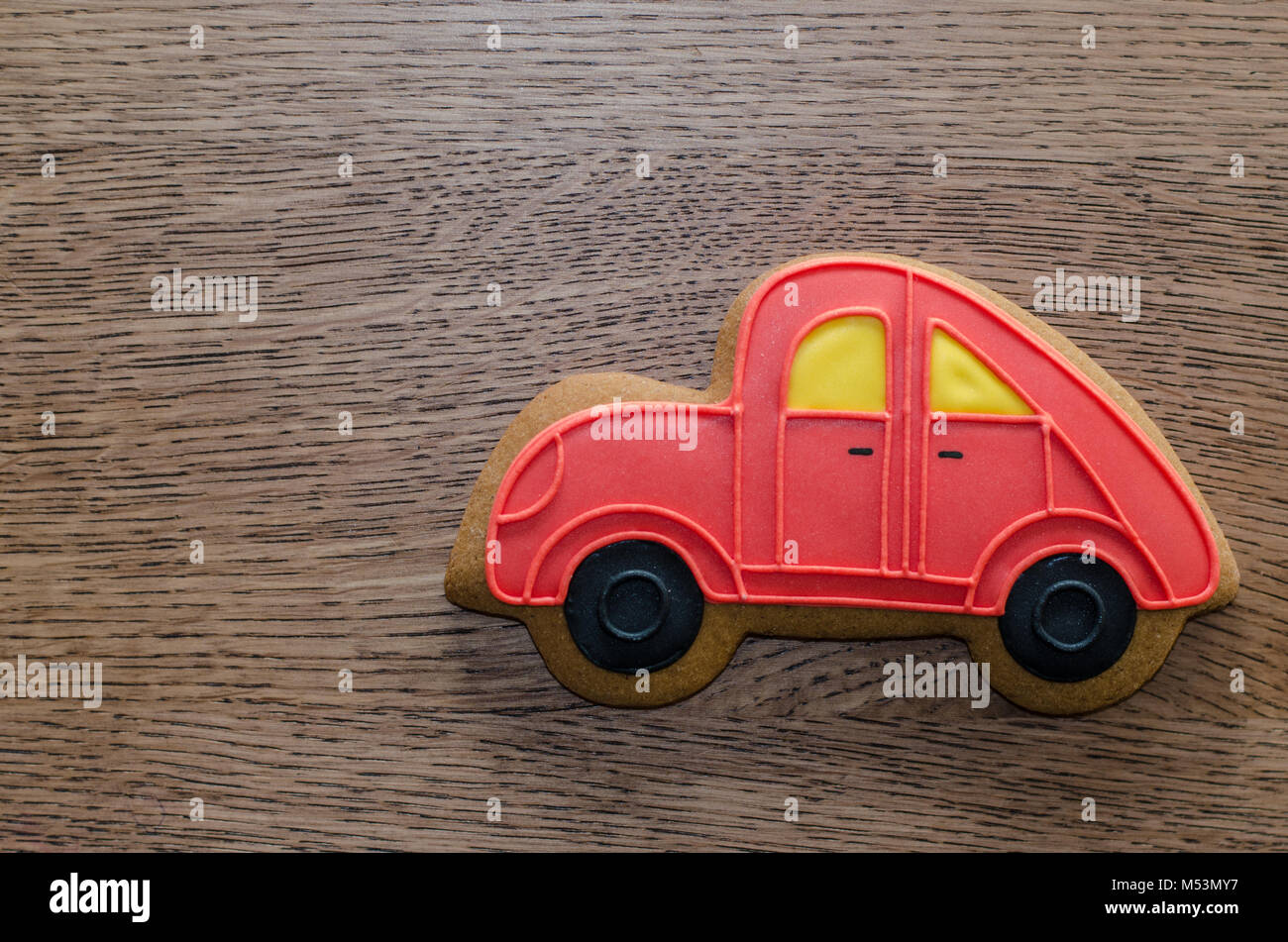 Close-up of red gingerbread car lying on the wooden table background ...