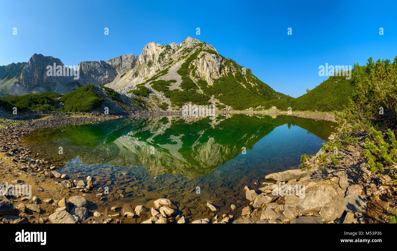 The vertical wall of mount Sinanitsa reflecting in Sinanishko lake ...