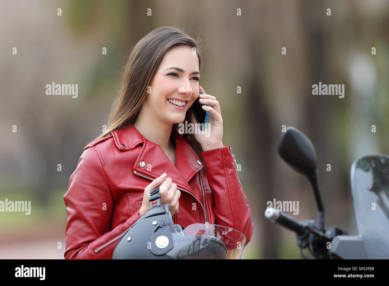 Happy motorbiker calling on mobile phone sitting on a motorbike Stock ...