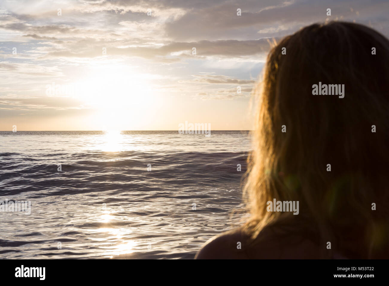 concept of the back of a woman's hair looking at the sun set across the ...