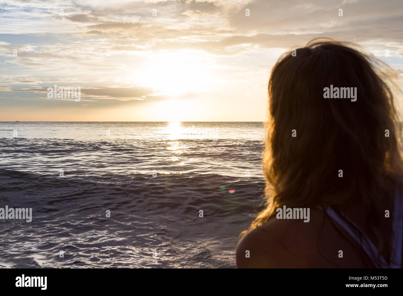 concept of the back of a woman's hair looking at the sun set across the ...