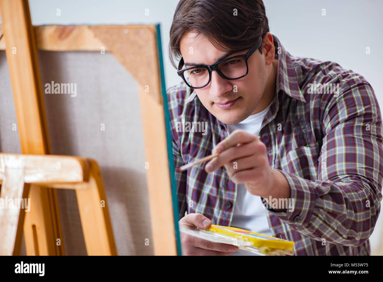 Young male artist drawing pictures in bright studio Stock Photo - Alamy