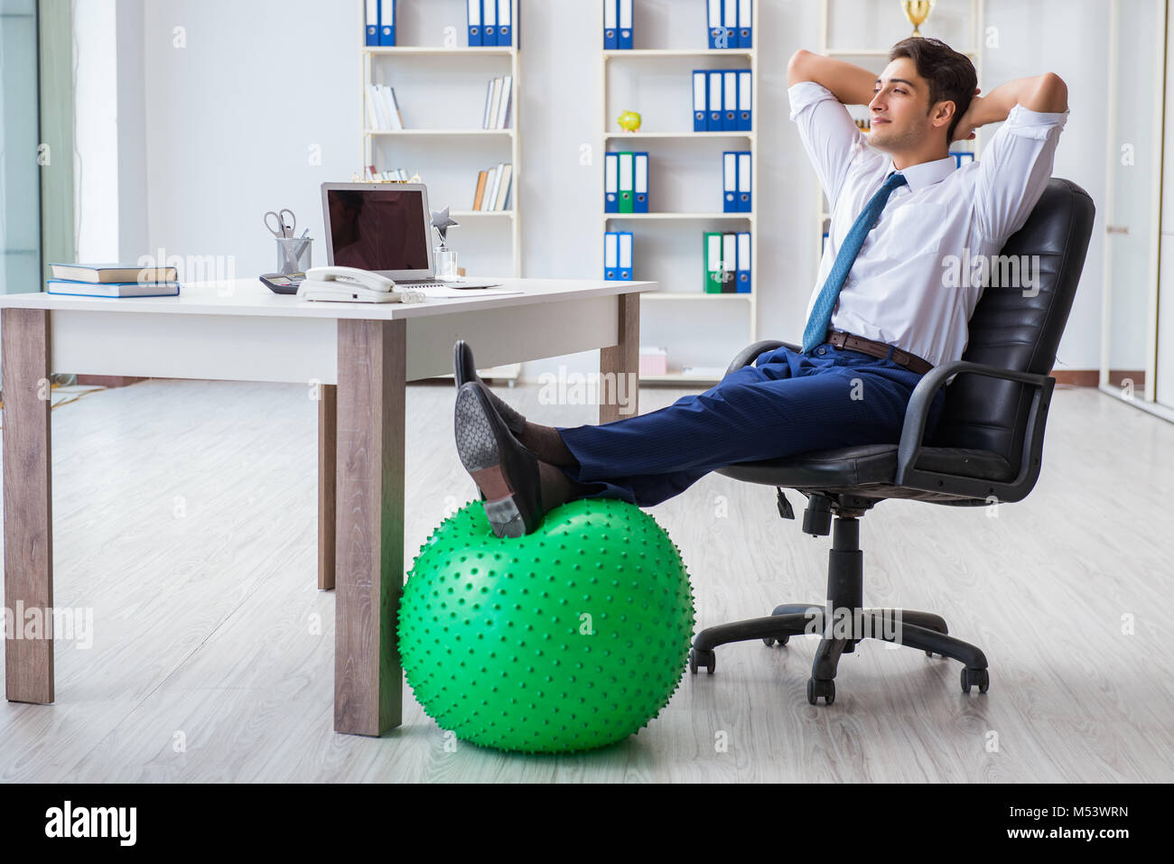 Young businessman doing sports stretching at workplace Stock Photo - Alamy