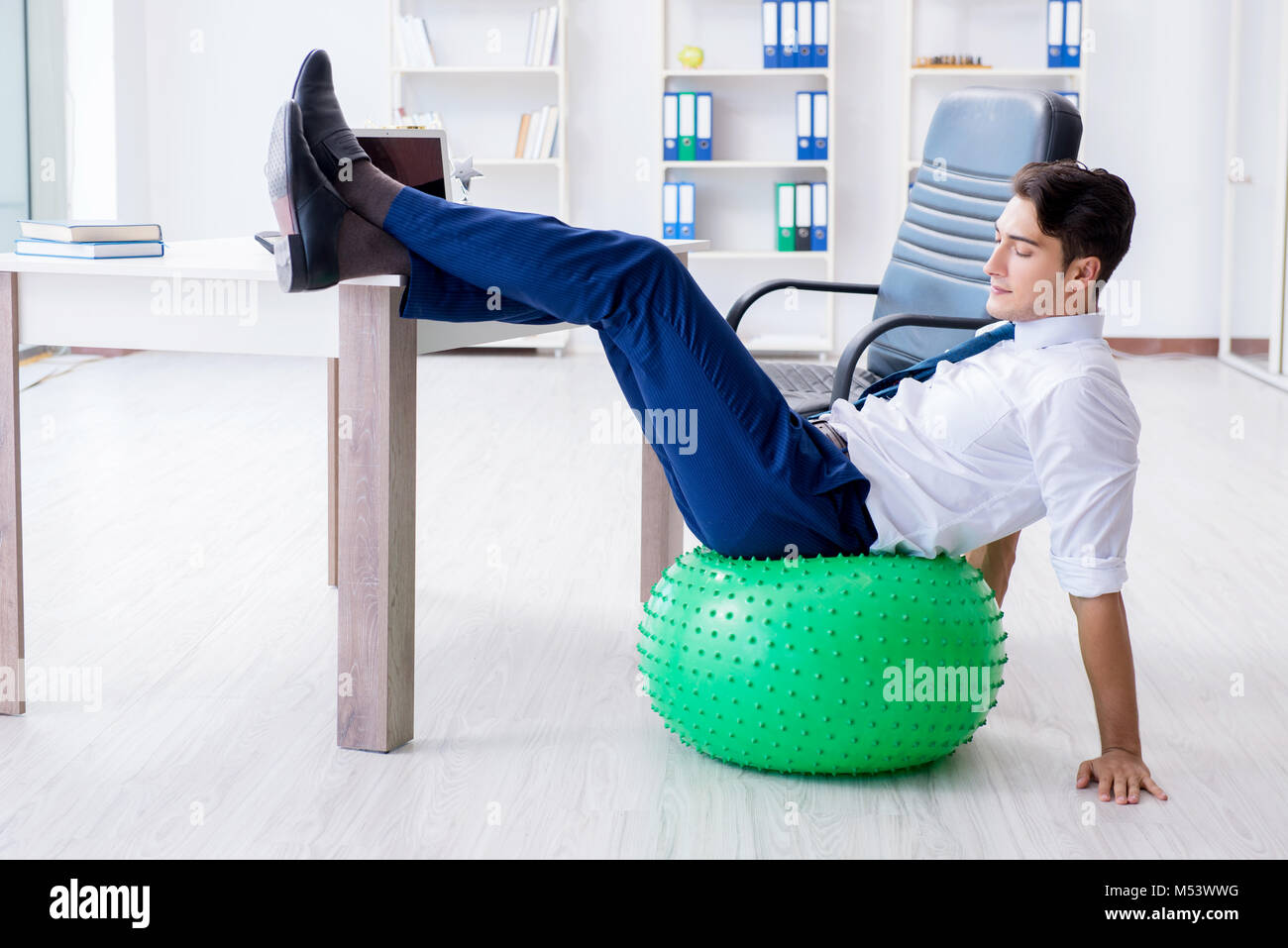 Young businessman doing sports stretching at workplace Stock Photo - Alamy