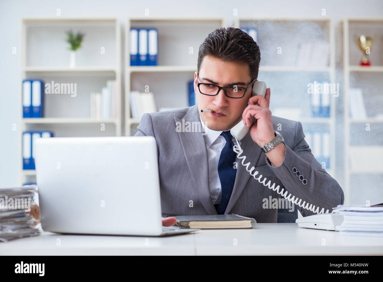 Businessman smoking in office at work Stock Photo - Alamy