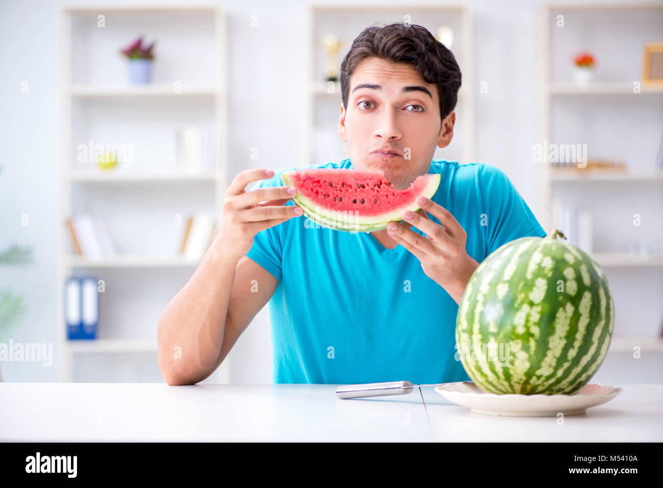 Man eating watermelon at home Stock Photo - Alamy