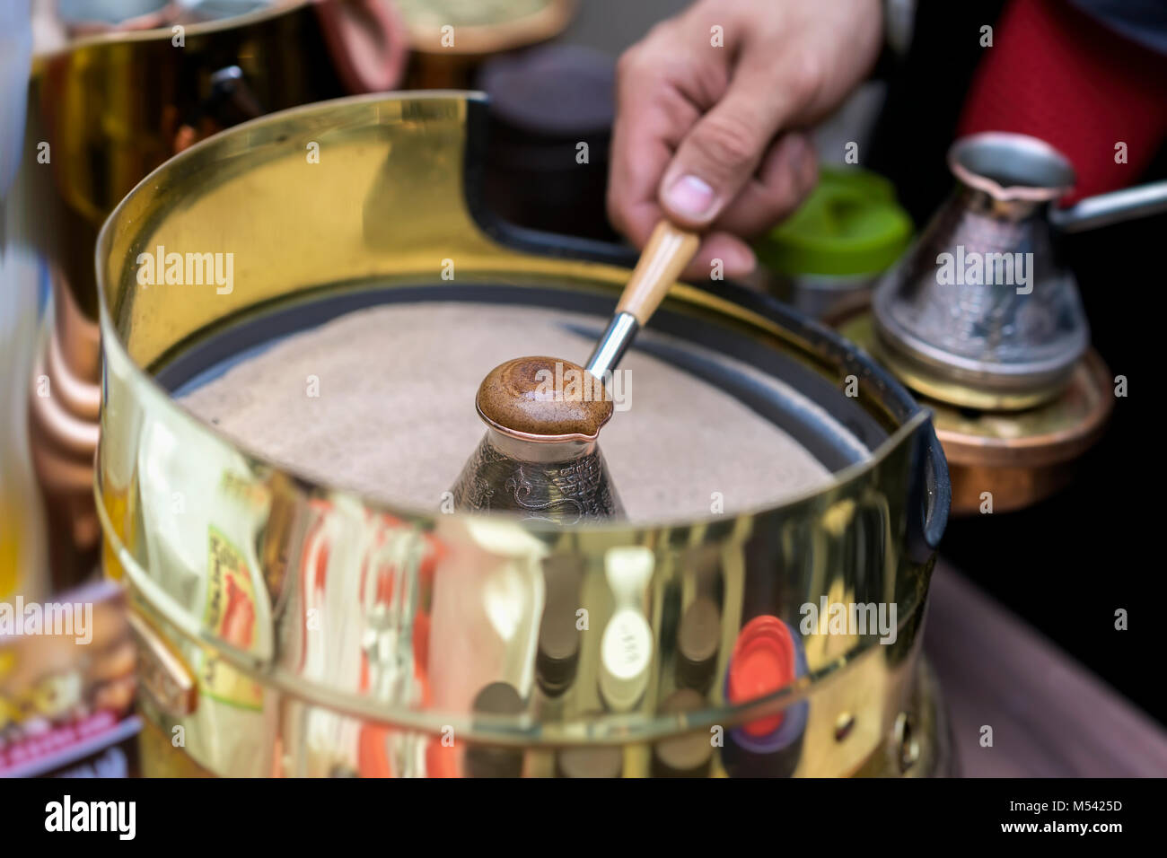 Close-up of hands of man making traditional turkish coffee with foam in ...