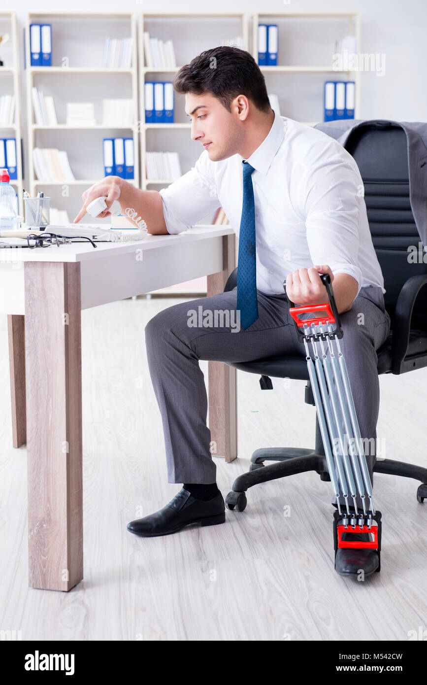 Young businessman exercising with elastic expander in office Stock ...
