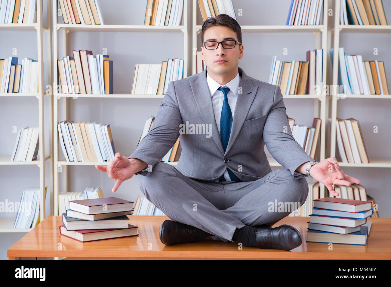 Businessman student in lotus position concentrating in the libr Stock ...