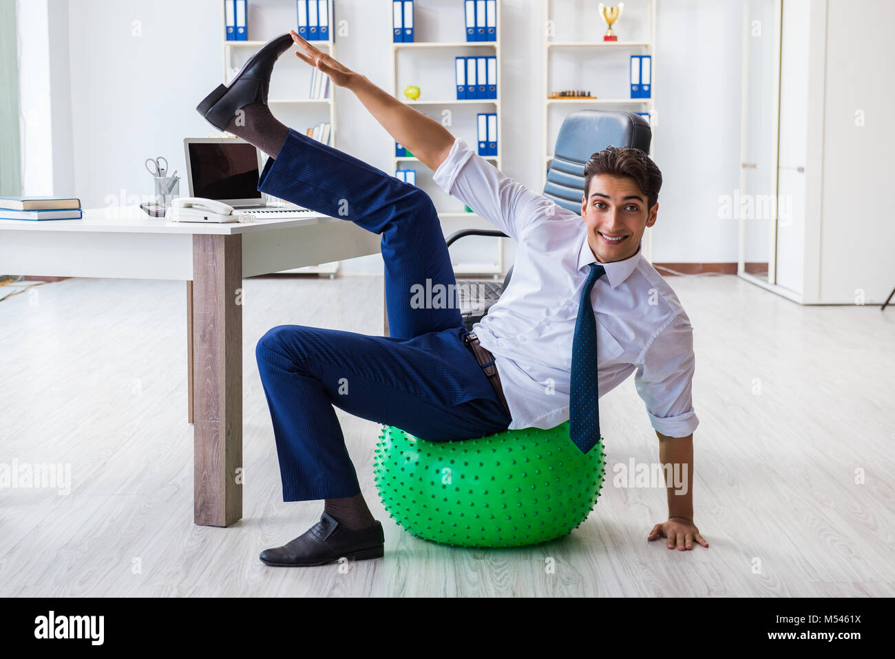 Young businessman doing sports stretching at workplace Stock Photo - Alamy