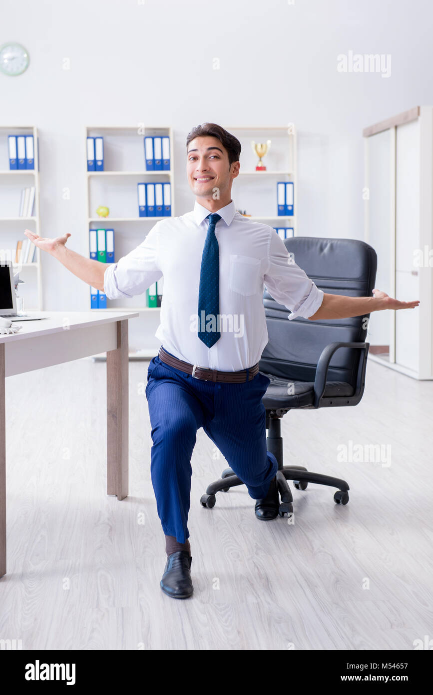Young businessman doing sports stretching at workplace Stock Photo - Alamy