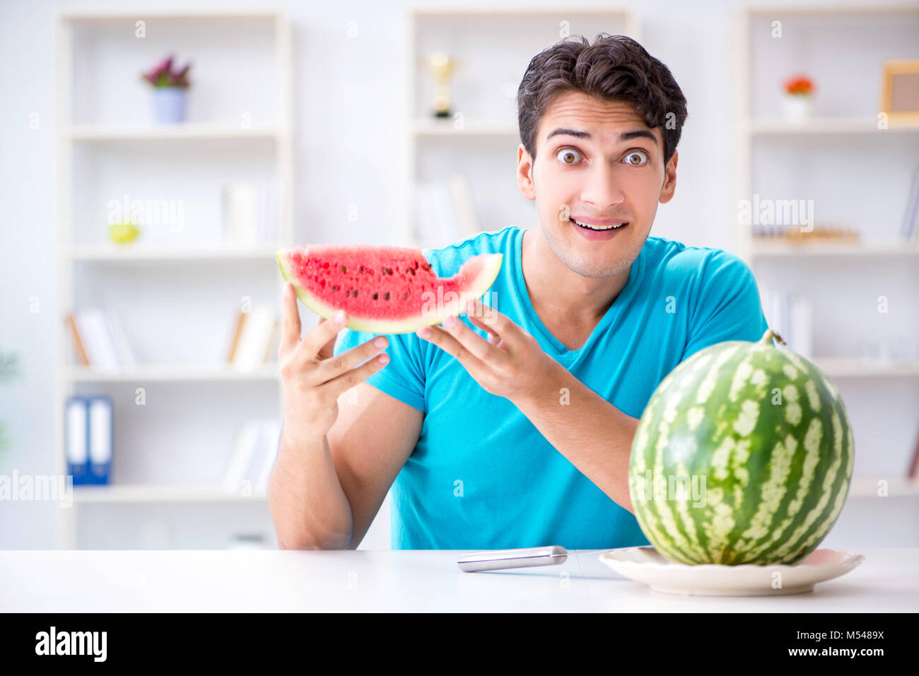 Man eating watermelon at home Stock Photo - Alamy