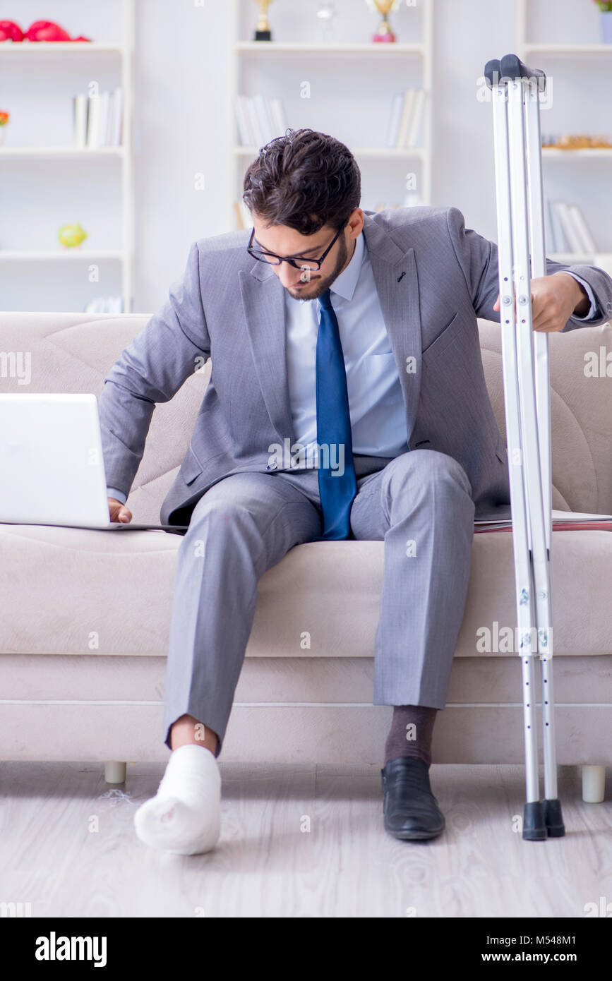 Businessman with crutches and broken leg at home working Stock Photo ...