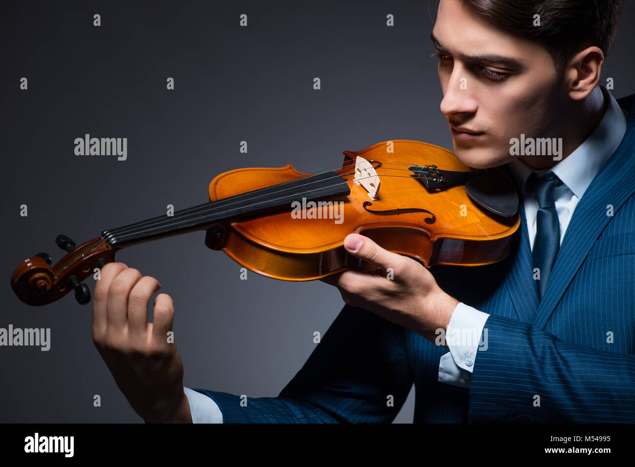 Young man playing violin in dark room Stock Photo - Alamy