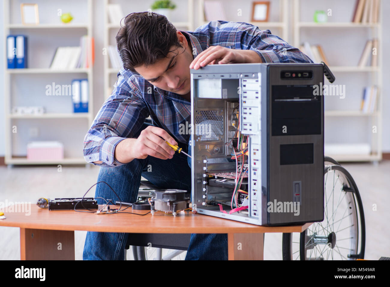 Disabled man on wheelchair repairing computer Stock Photo - Alamy