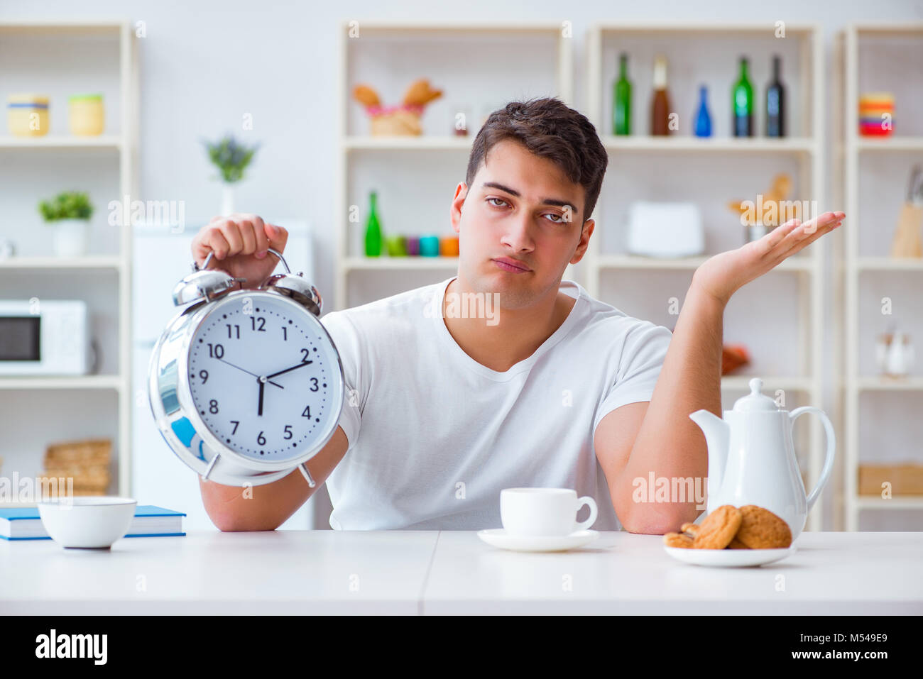 Man with alarm clock falling asleep at breakfast Stock Photo - Alamy