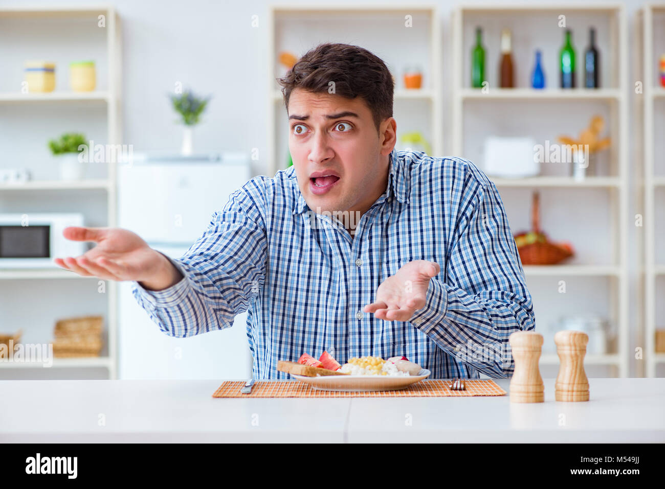 Young husband eating tasteless food at home for lunch Stock Photo - Alamy