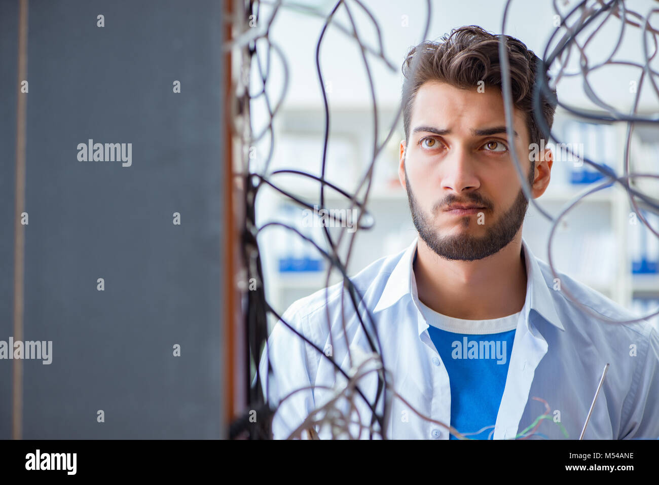 Electrician trying to untangle wires in repair concept Stock Photo - Alamy