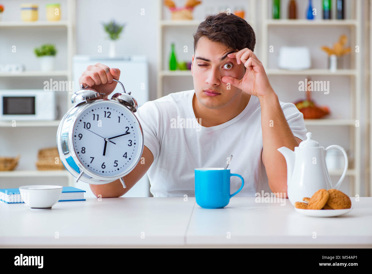 Man with alarm clock falling asleep at breakfast Stock Photo - Alamy