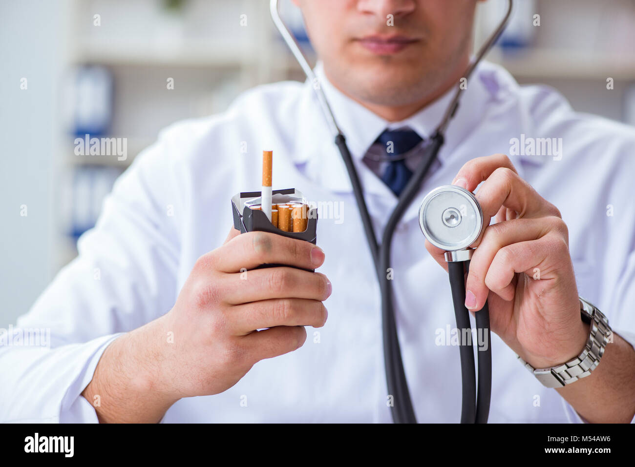 Male doctor in anti-smoking conceptwithcigarette pack Stock Photo - Alamy