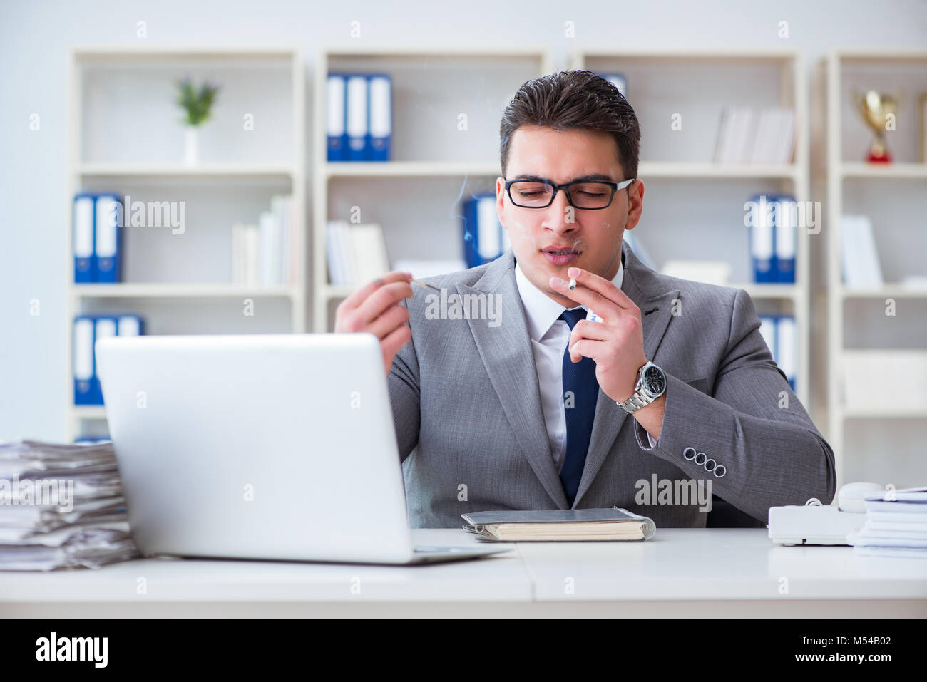 Businessman smoking in office at work Stock Photo - Alamy