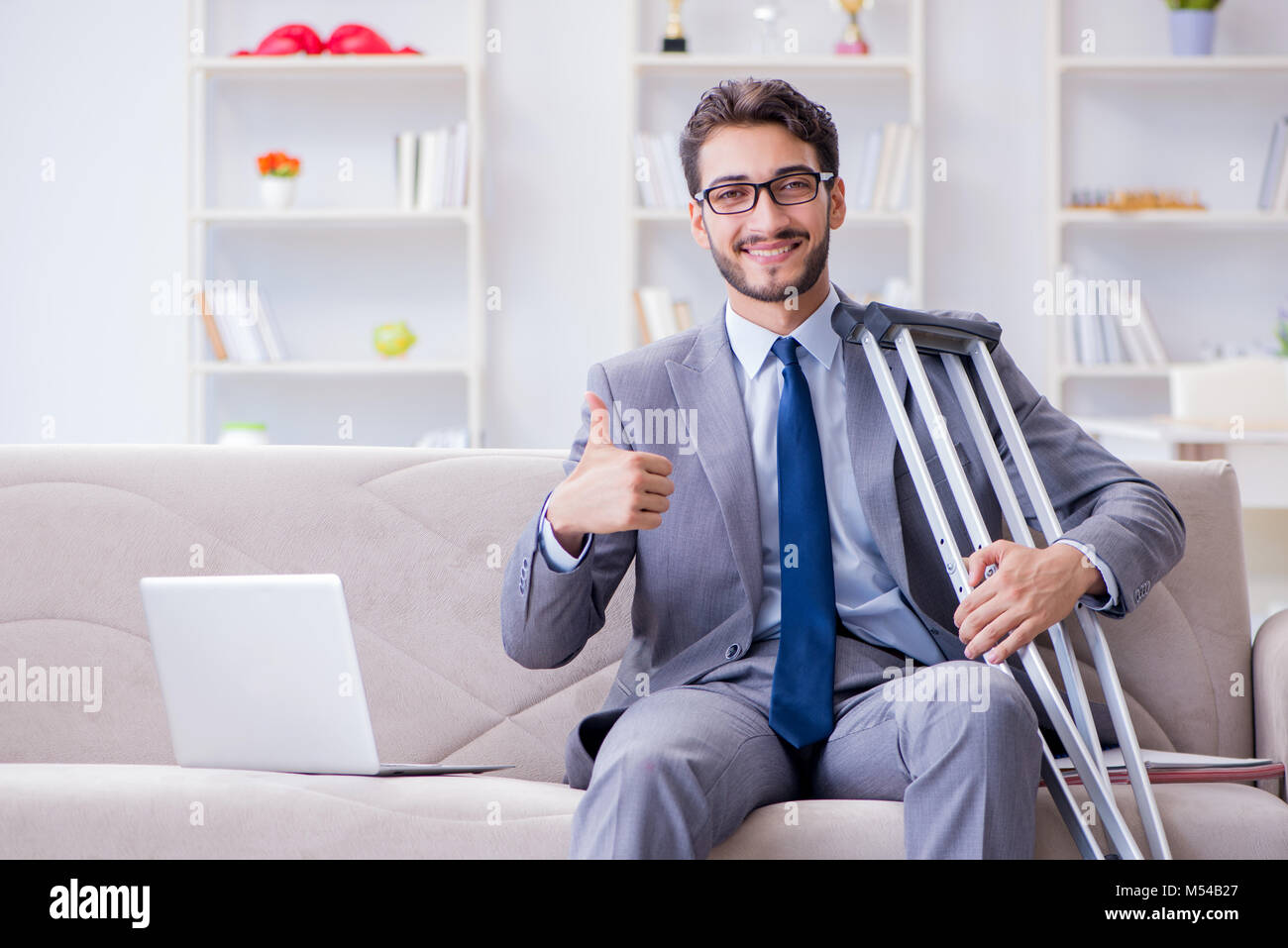 Businessman with crutches and broken leg at home working Stock Photo ...