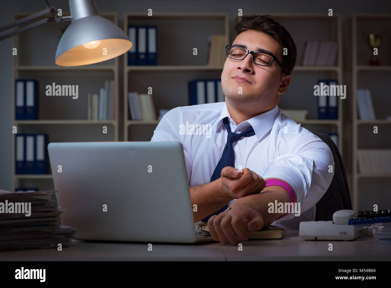 Businessman staying late in office for drugs Stock Photo - Alamy