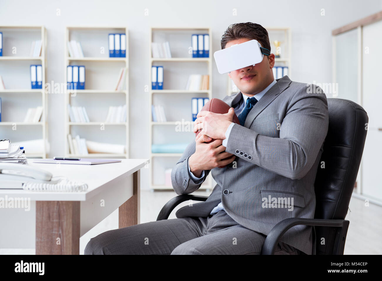 Businessman playing virtual reality football in office with VR g Stock ...