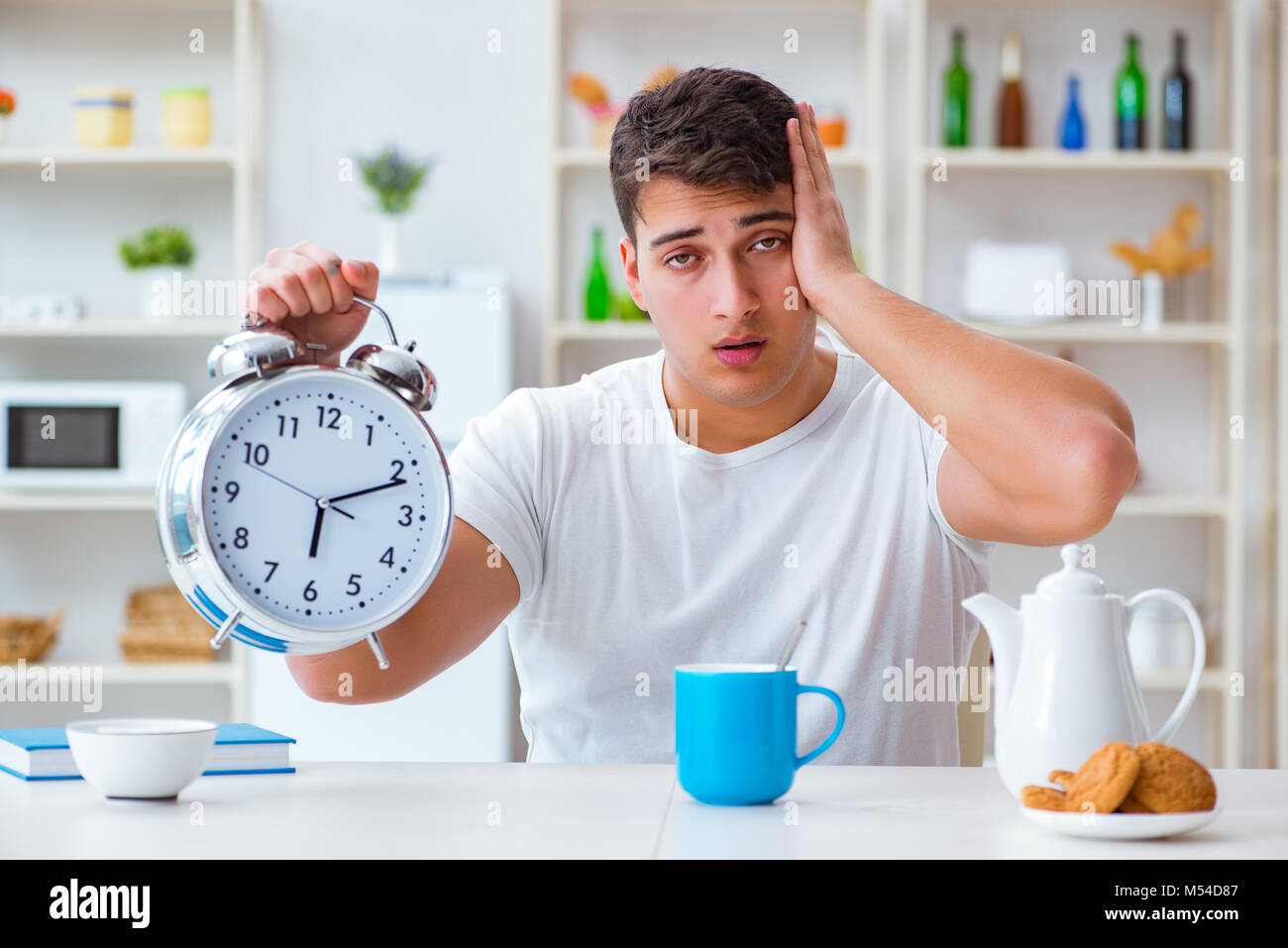 Man with alarm clock falling asleep at breakfast Stock Photo - Alamy