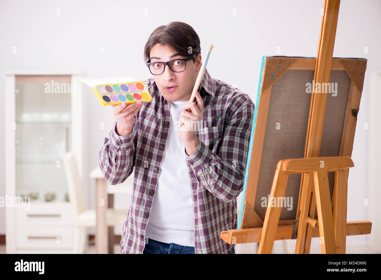Young male artist drawing pictures in bright studio Stock Photo - Alamy