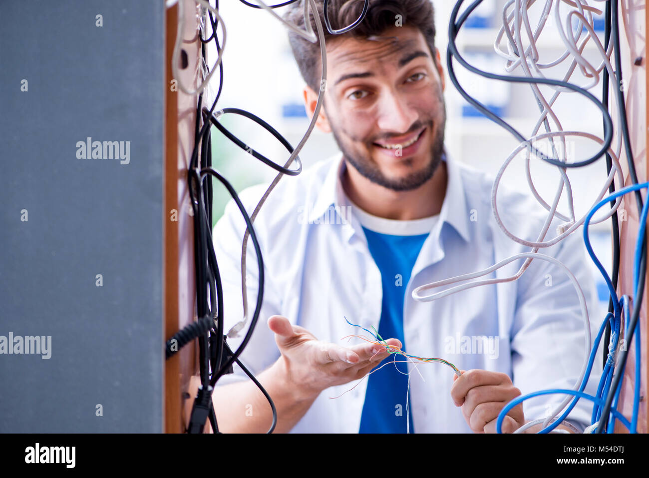 Electrician trying to untangle wires in repair concept Stock Photo - Alamy