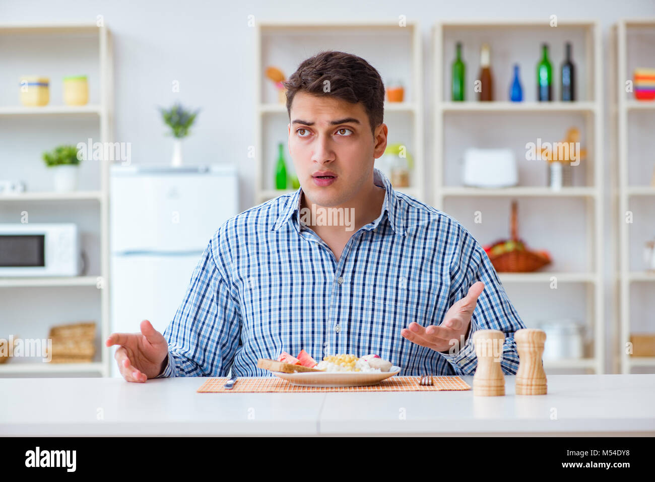 Young husband eating tasteless food at home for lunch Stock Photo - Alamy