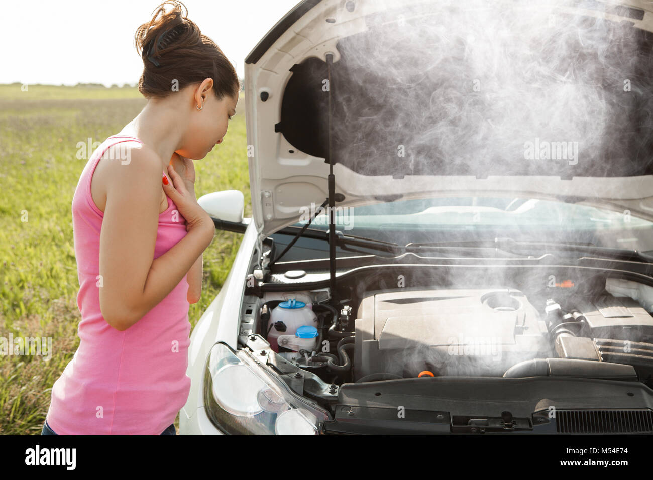 Frustrated Young Woman Looking Under The Hood Of Breakdown Car Stock Photo - Alamy