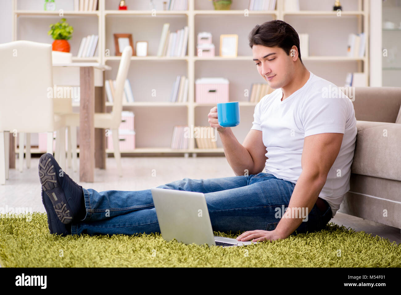 Man working on laptop at home on carpet floor Stock Photo - Alamy