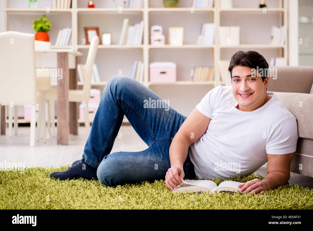 Man reading book at home on floor Stock Photo - Alamy