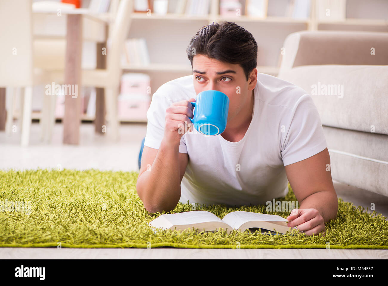 Man reading book at home on floor Stock Photo - Alamy