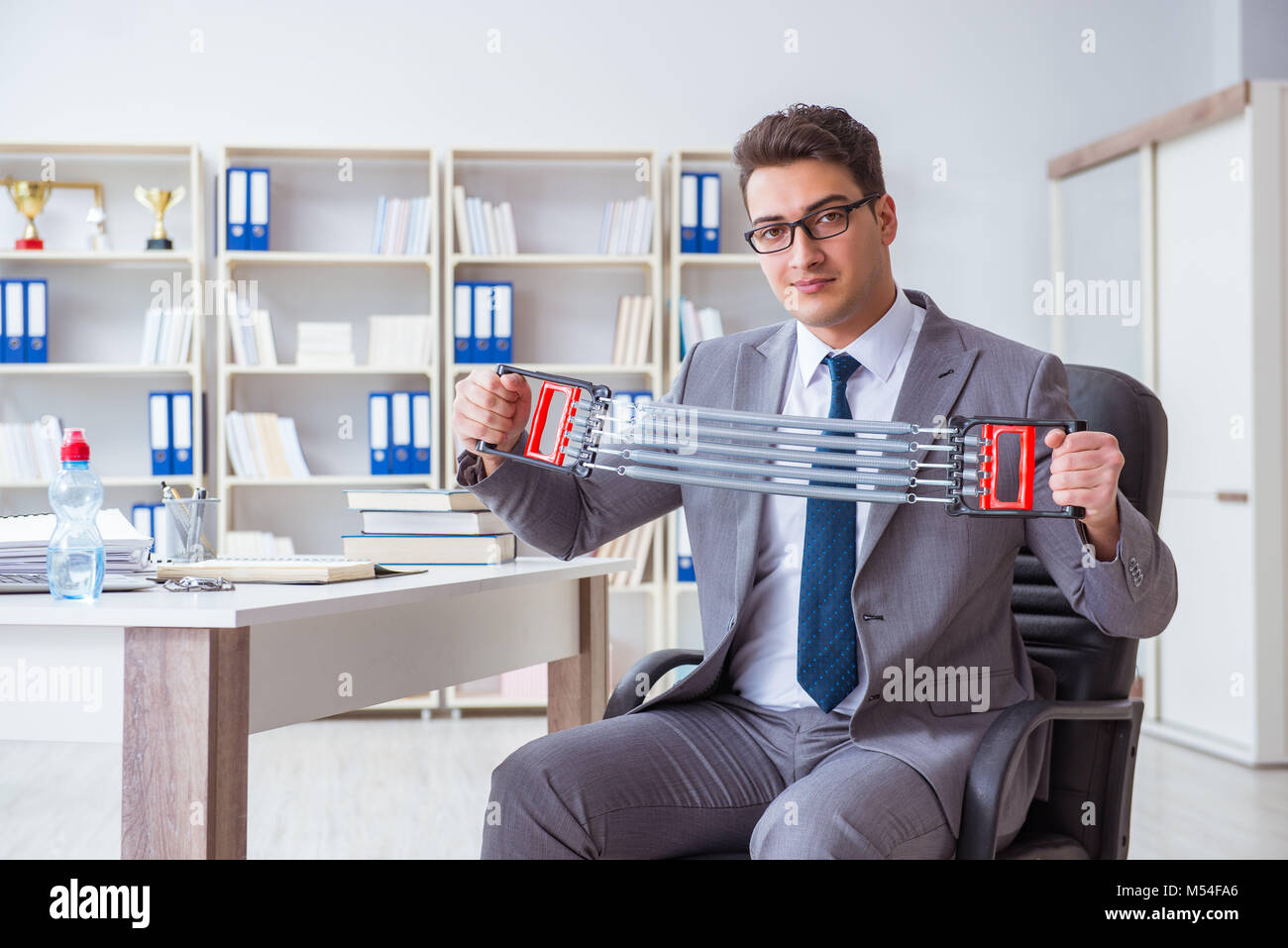 Young businessman exercising with elastic expander in office Stock ...