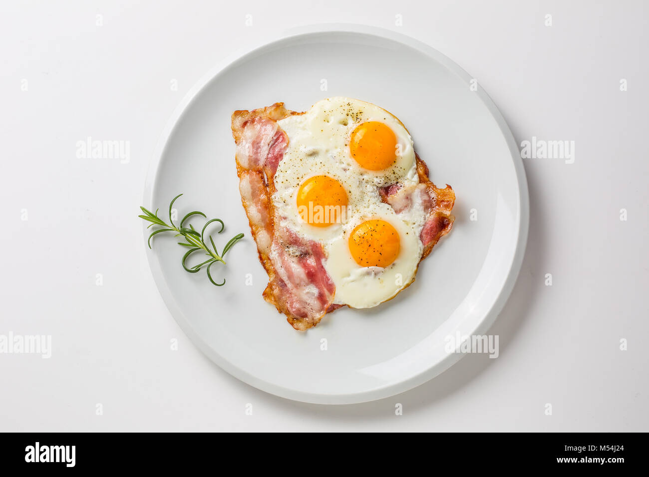Ham and Eggs. Bacon and Eggs. Salted egg with pepper on white plate ...