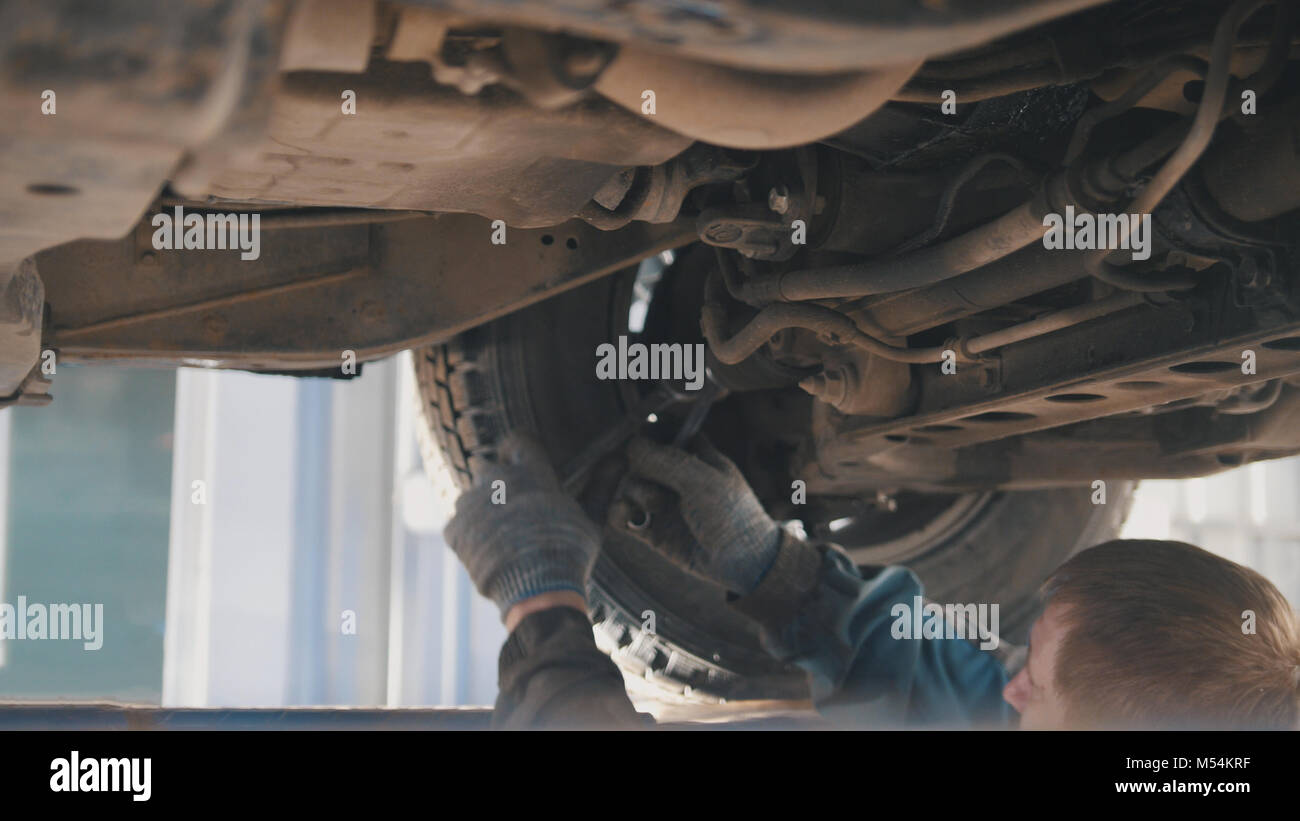 Automobile service - mechanic wrapping working device under car bottom ...