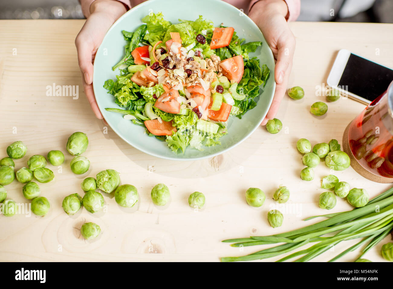 Holding a plate with green salad on the table Stock Photo - Alamy