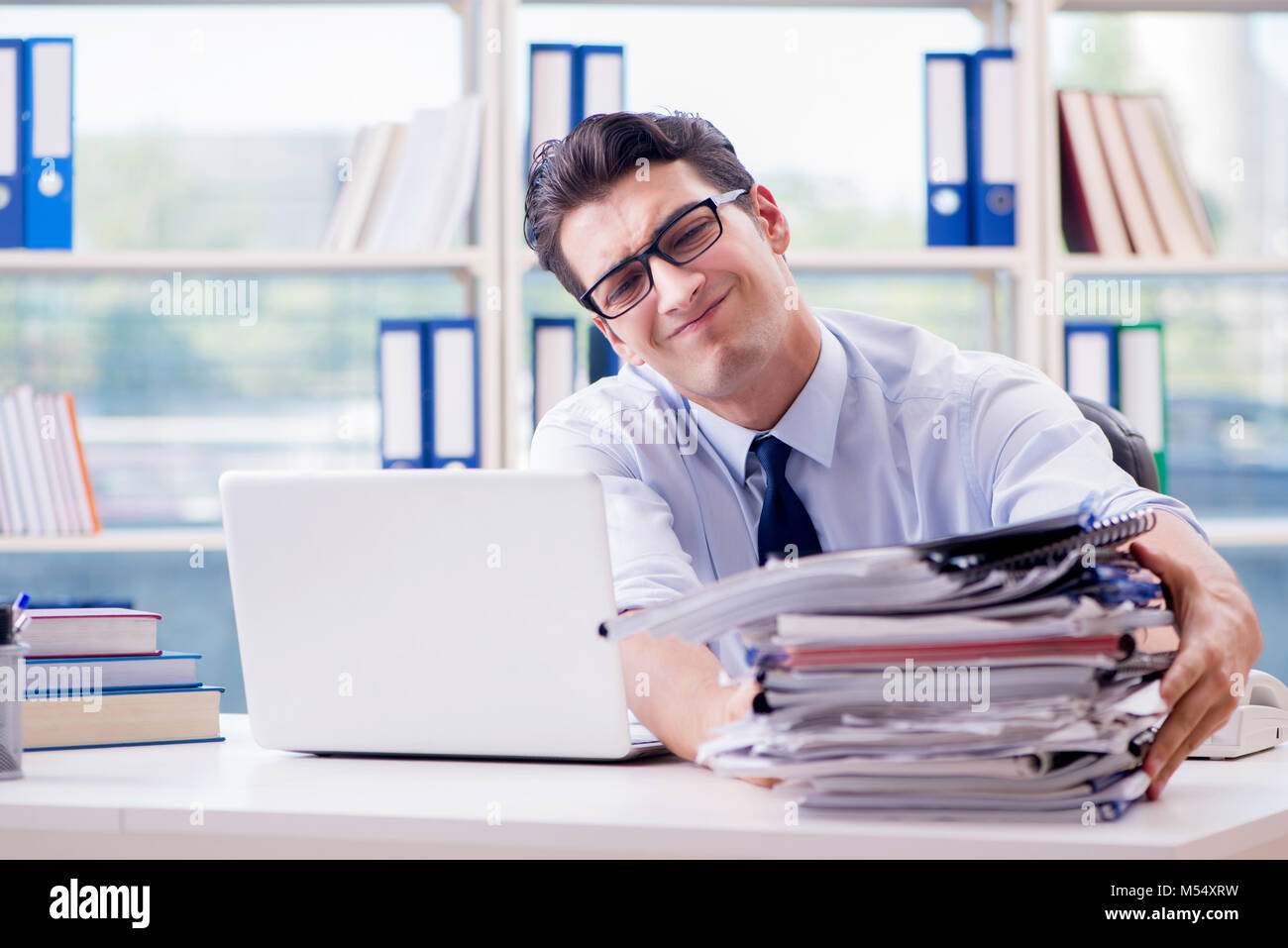 The businessman with excessive work paperwork working in office Stock ...