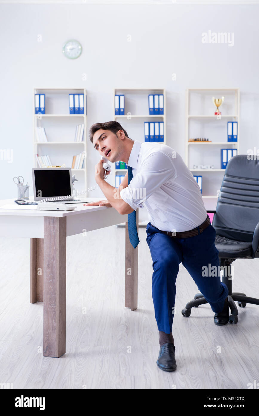 The young businessman doing sports stretching at workplace Stock Photo ...