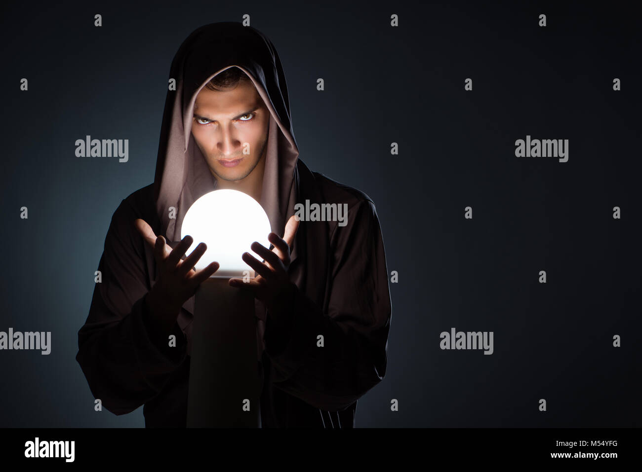 The young wizard with crystal ball in dark room Stock Photo - Alamy